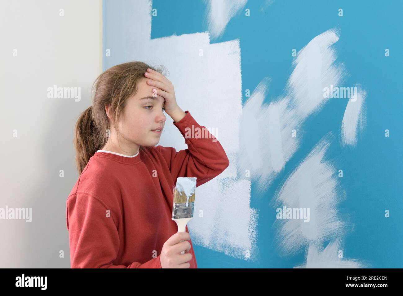 Teenage girl has headache at first time paints the wall. Girl painting ...