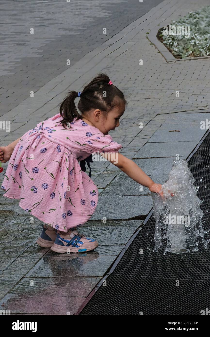 Kazakhstan, Almaty. Little Kazakh Girl Investigating Fountains on the ...