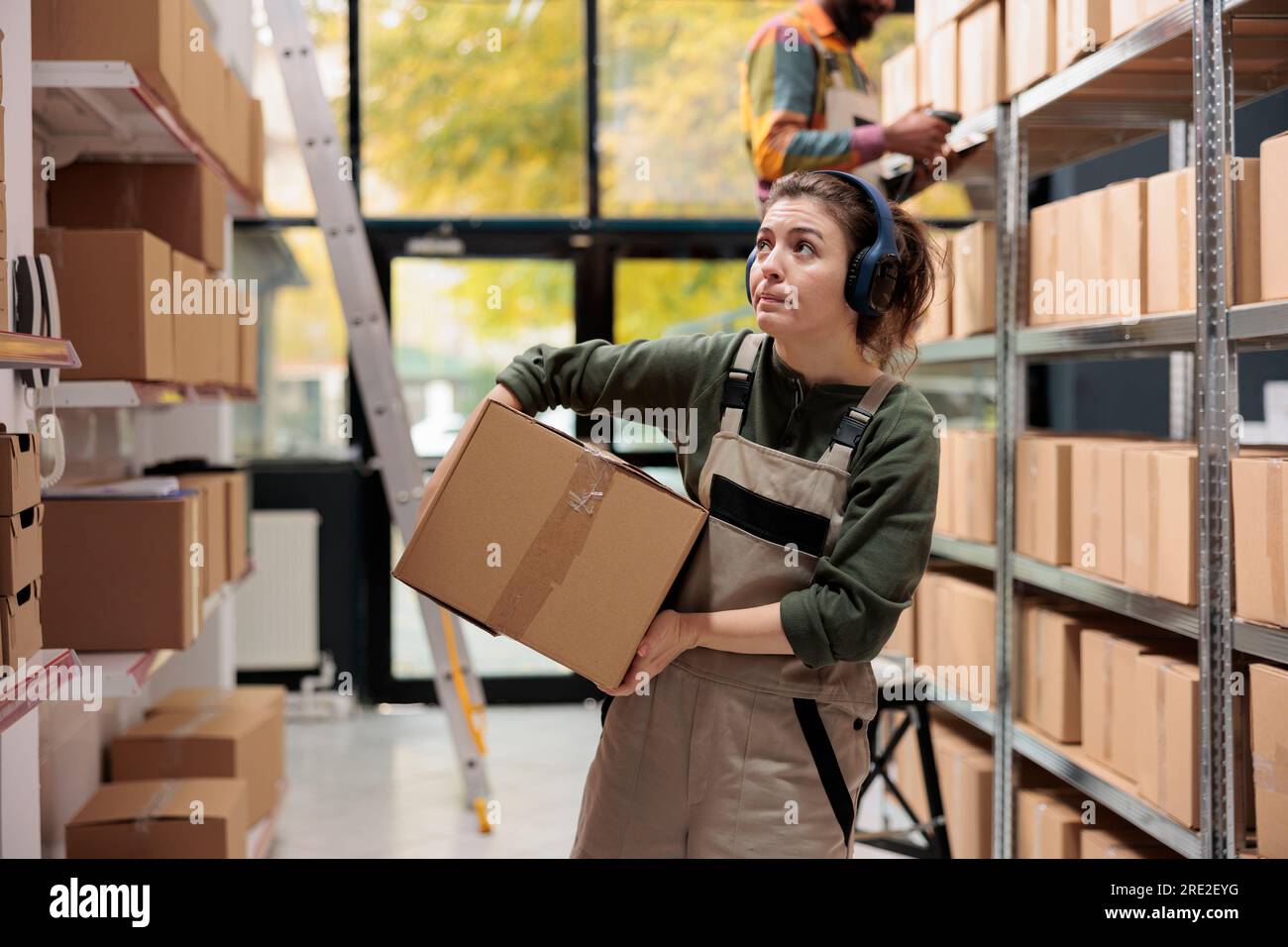 Storage room manager looking at shelves full with boxes, wearing ...