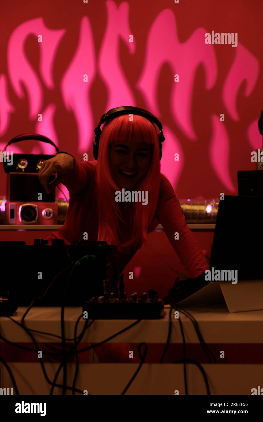 Artist with pink hair wearing headset while playing techno song at ...
