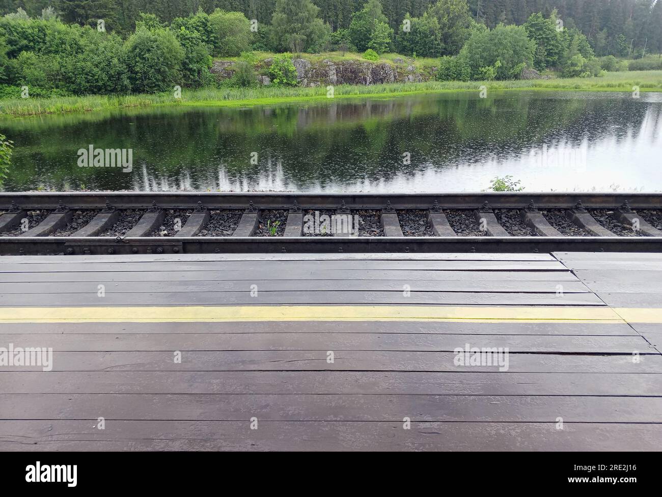 Railway track by the wooden platform and lake Stock Photo - Alamy