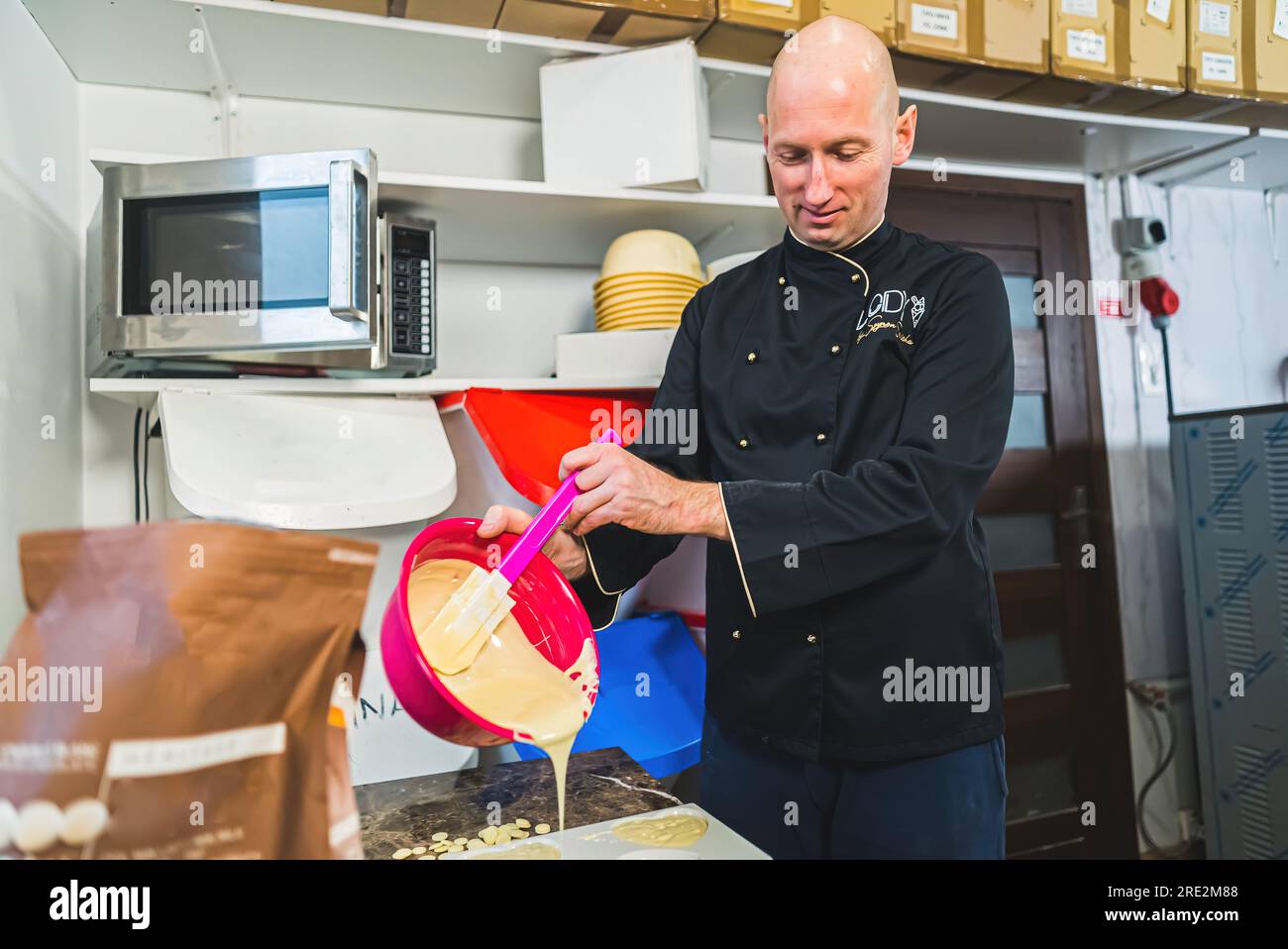 Chocolate production concept. Bald caucasian male chef pouring melted ...