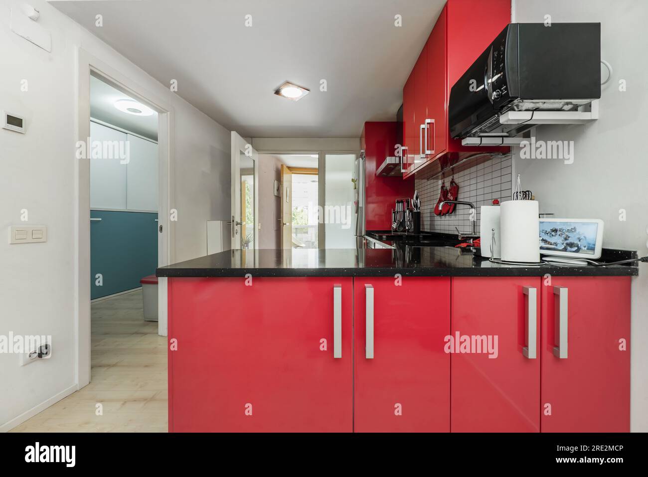 Open plan kitchen of bright red cabinets with black granite worktop in ...