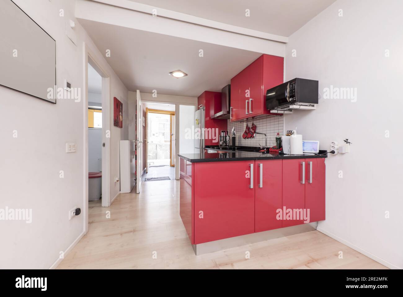 Open kitchen of bright red cabinets with black granite countertops in a ...