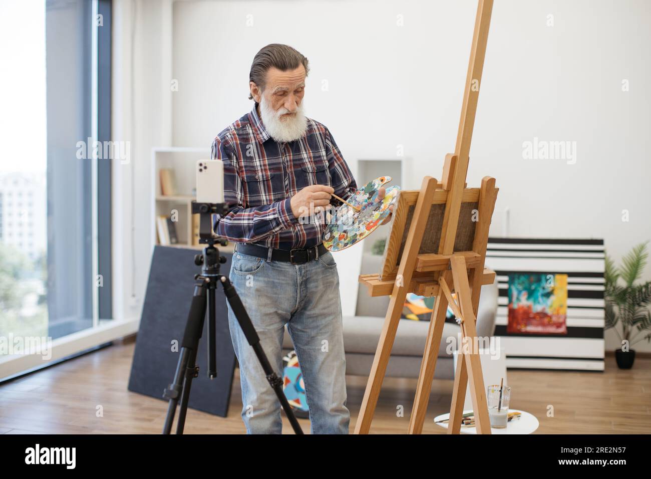 Senior drawing expert making live streaming from spacious apartment ...