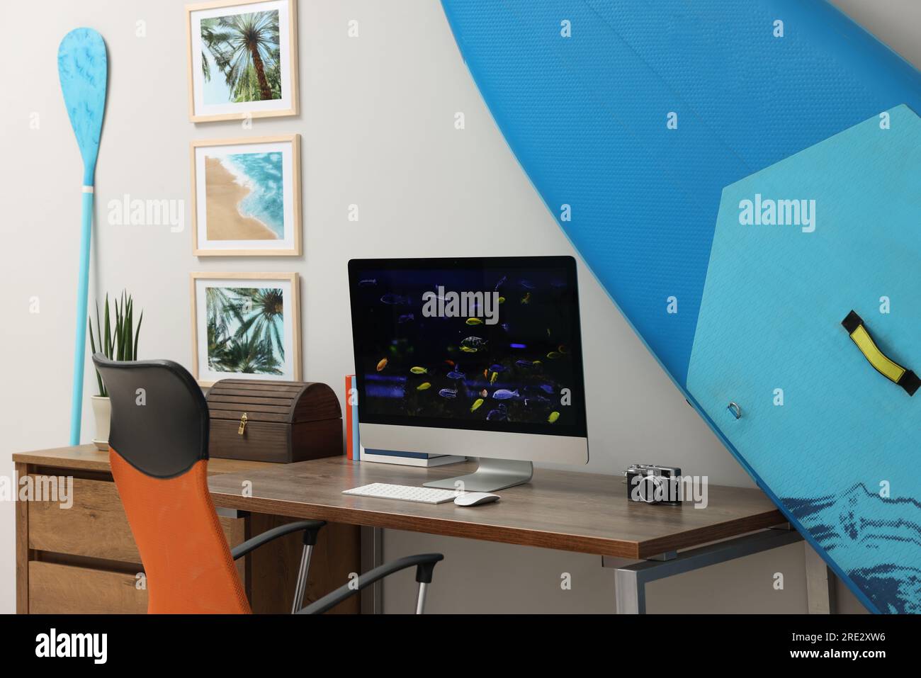 Stylish workplace with modern computer and SUP board near light wall in ...