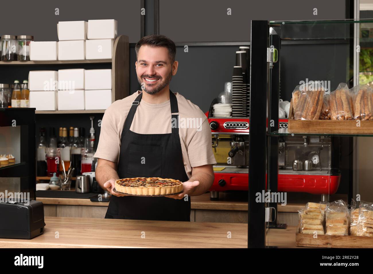 Business owner in his cafe. Man presenting delicious quiche at desk ...