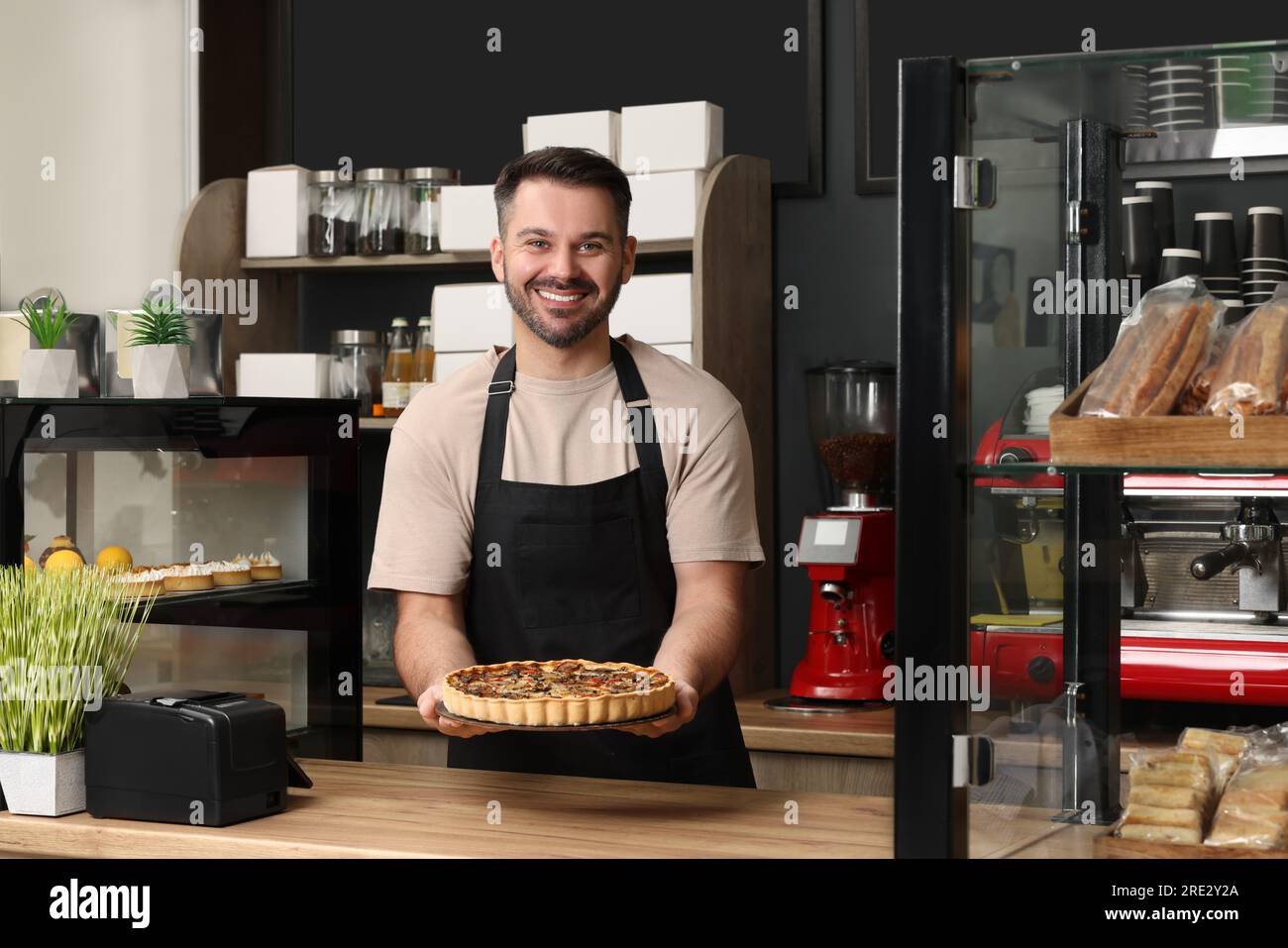 Business owner in his cafe. Man presenting delicious quiche at desk ...