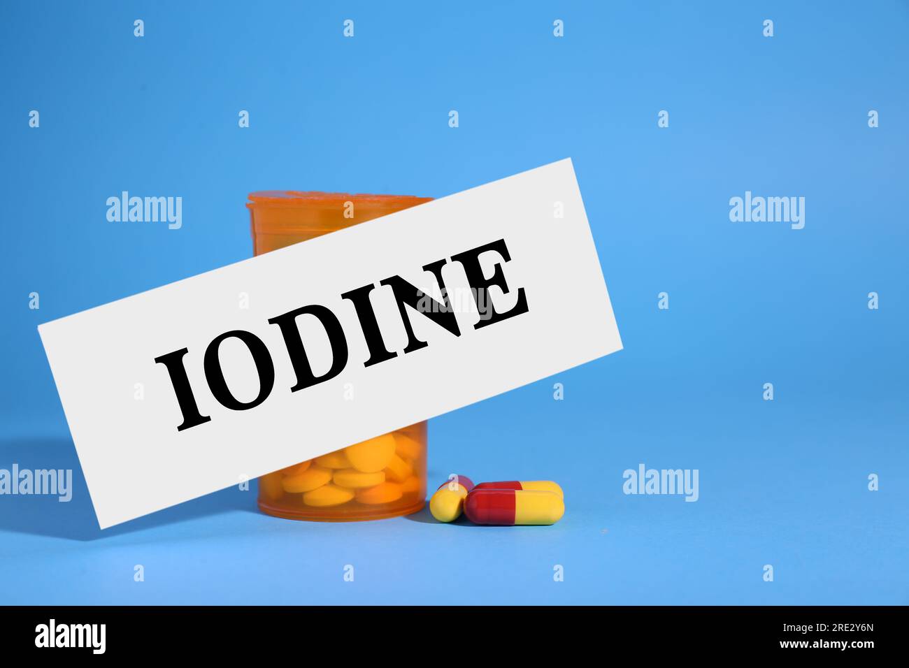 Paper note with word Iodine, bottle and pills on light blue background ...