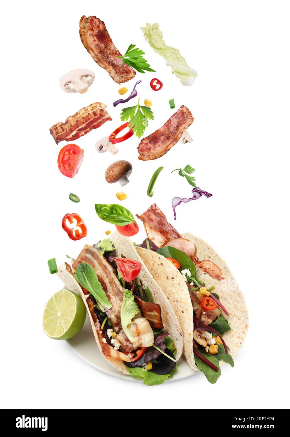 Delicious tacos. Ingredients falling into tortillas on white background ...