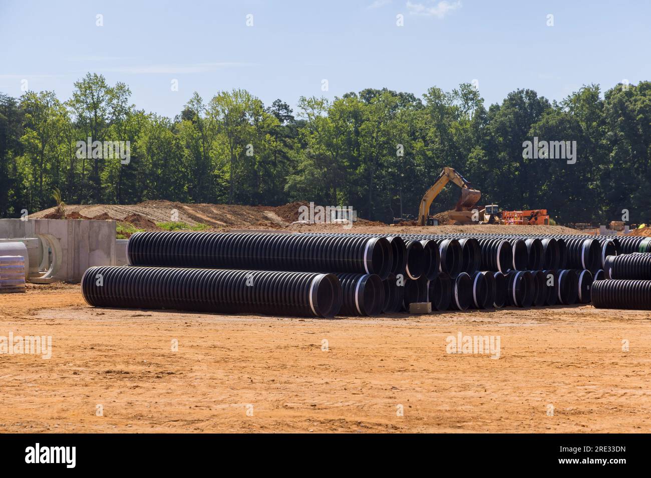 On construction site, stacks of large black plastic pipes ready for ...