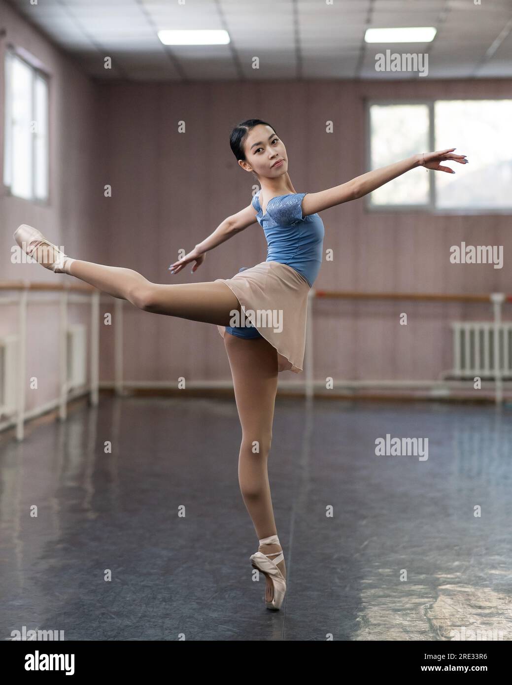 Graceful Asian ballerina in a blue bodysuit and a beige skirt is ...