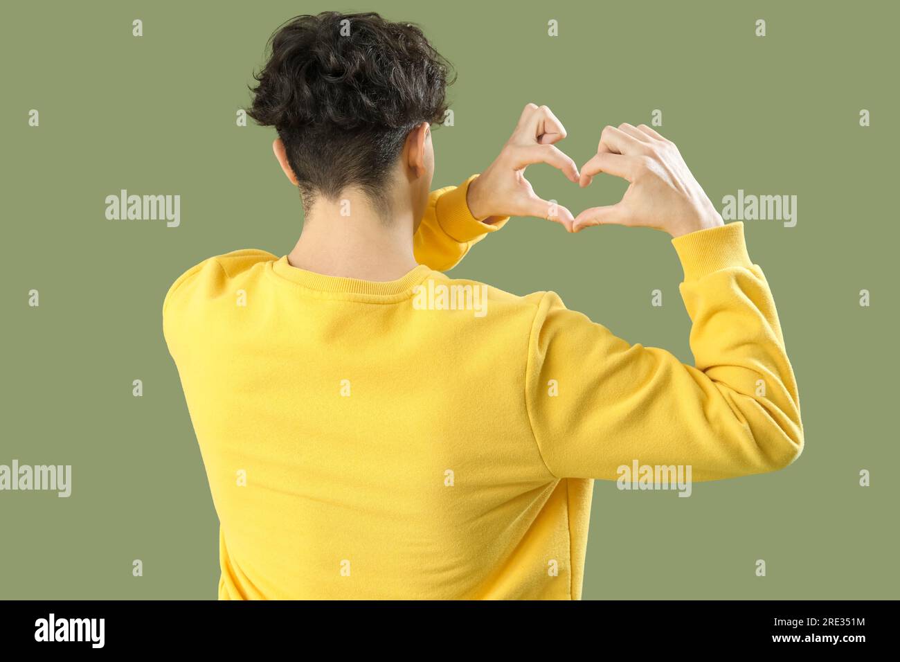 Handsome young man making heart with his hands on green background ...