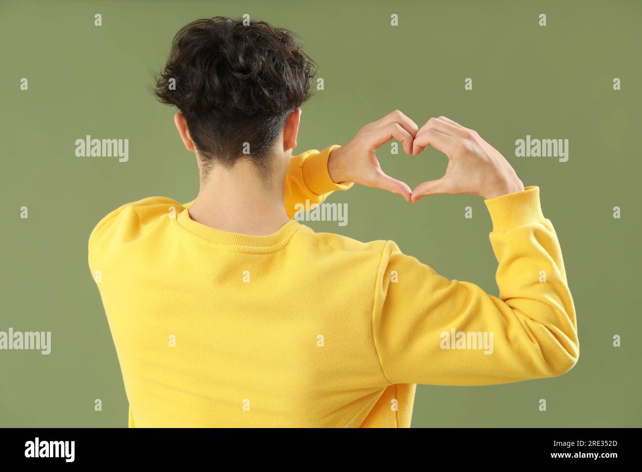 Handsome young man making heart with his hands on green background ...