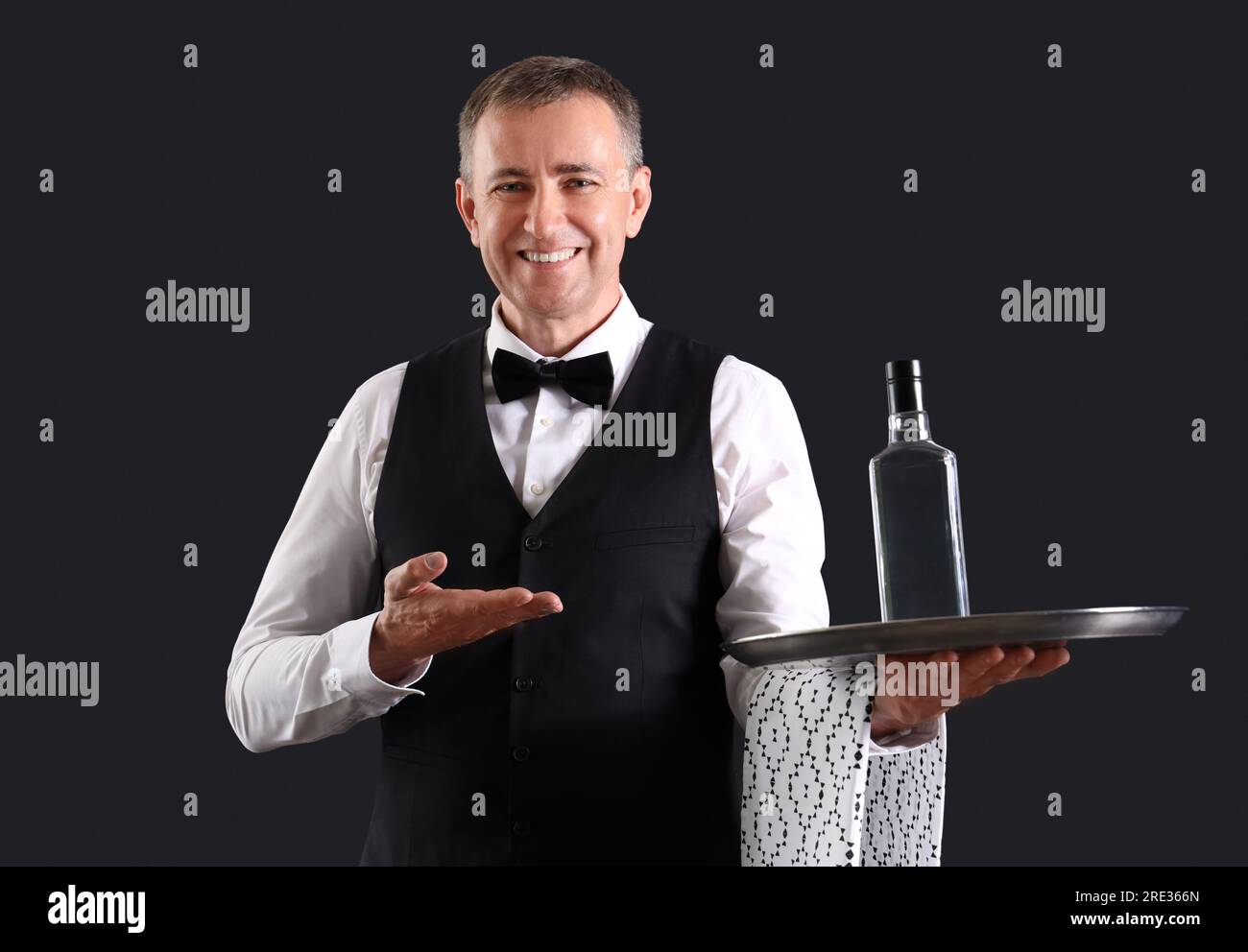 Mature waiter with bottle of vodka on black background Stock Photo - Alamy