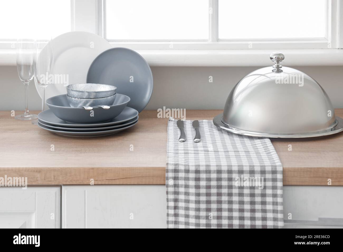 Kitchen counter with clean dishes and cloche near window Stock Photo ...