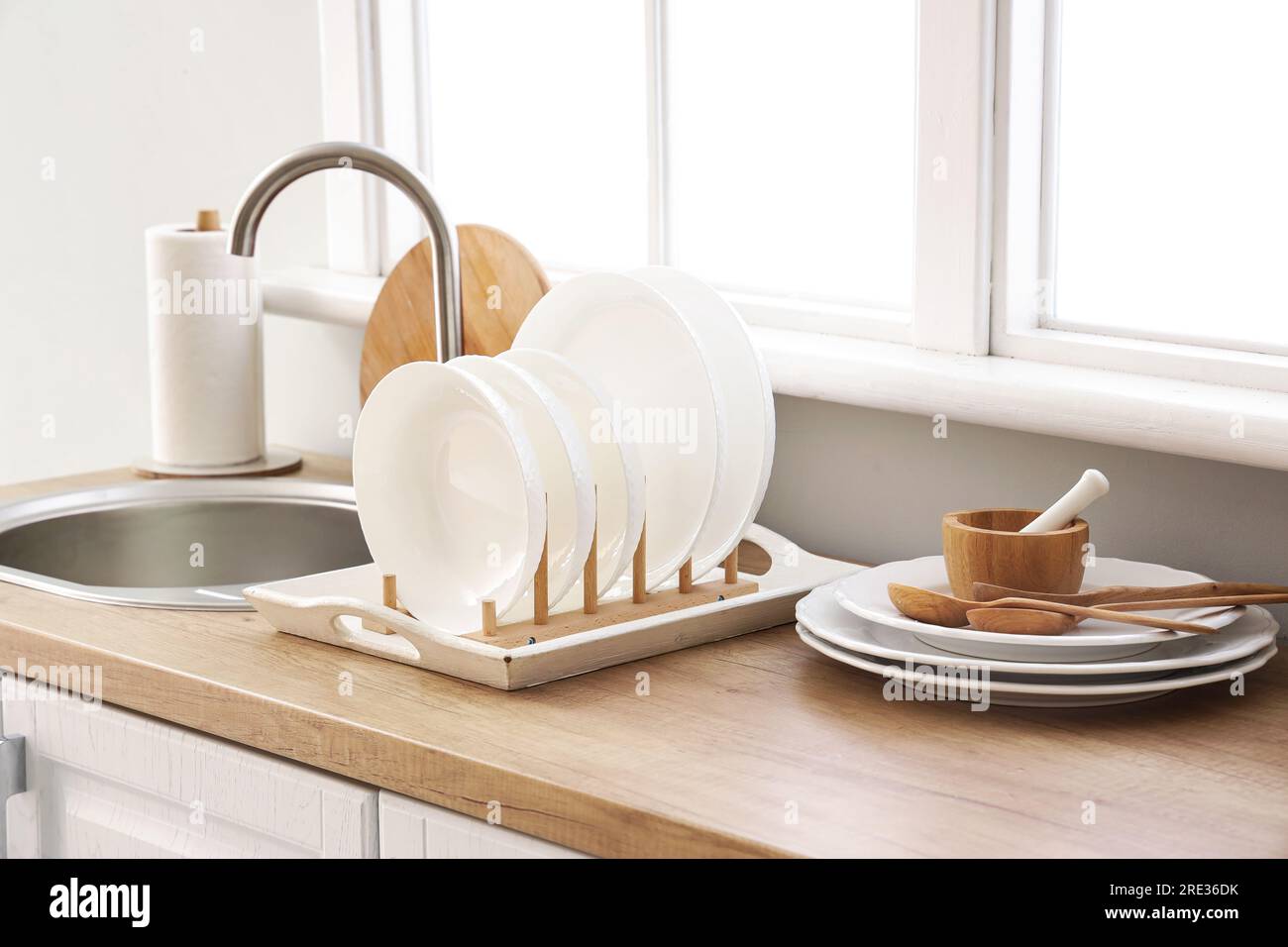 Kitchen counter with sink, plate rack and clean dishes near window ...