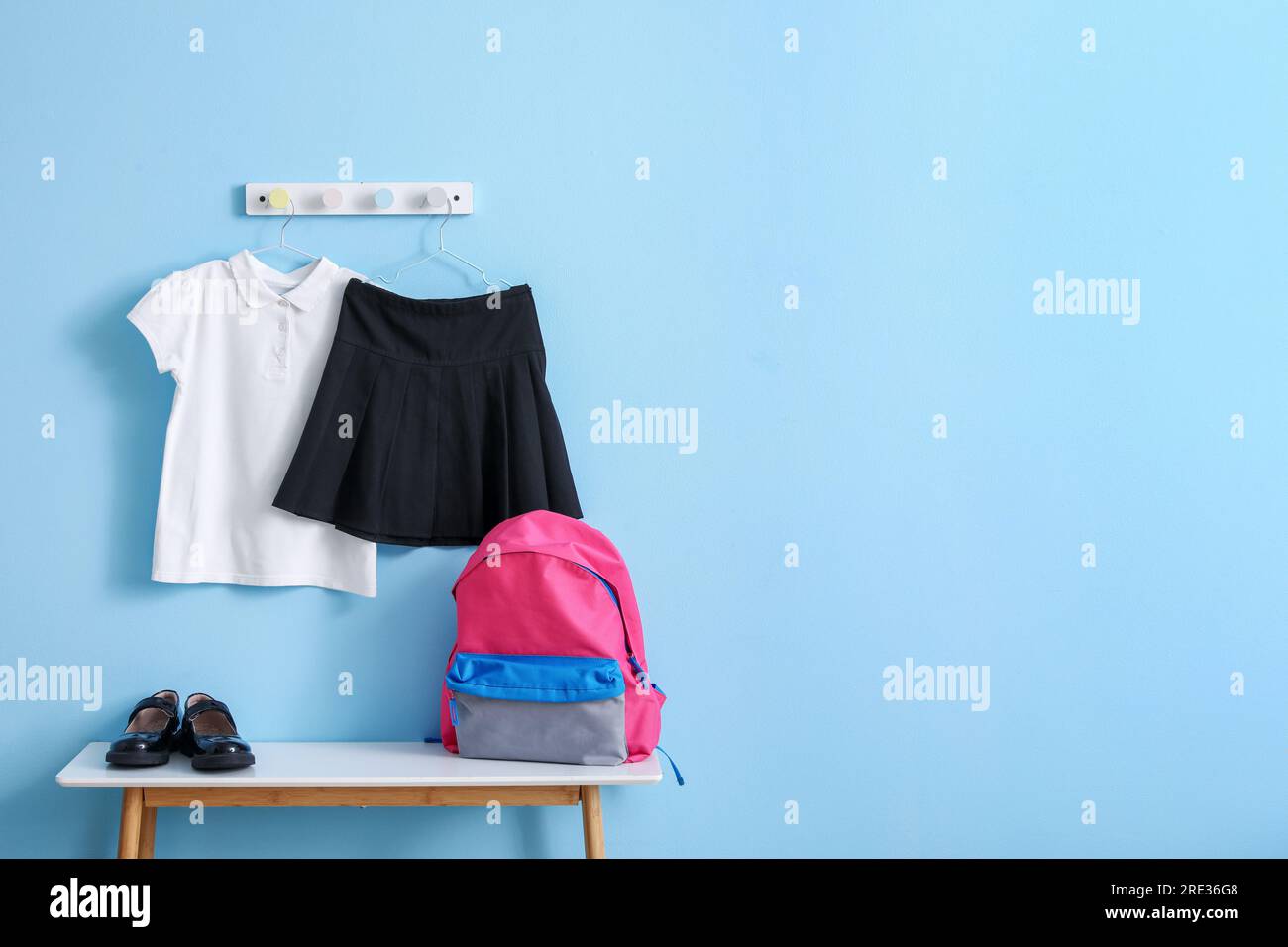 Table with backpack, shoes and stylish school uniform hanging on blue ...