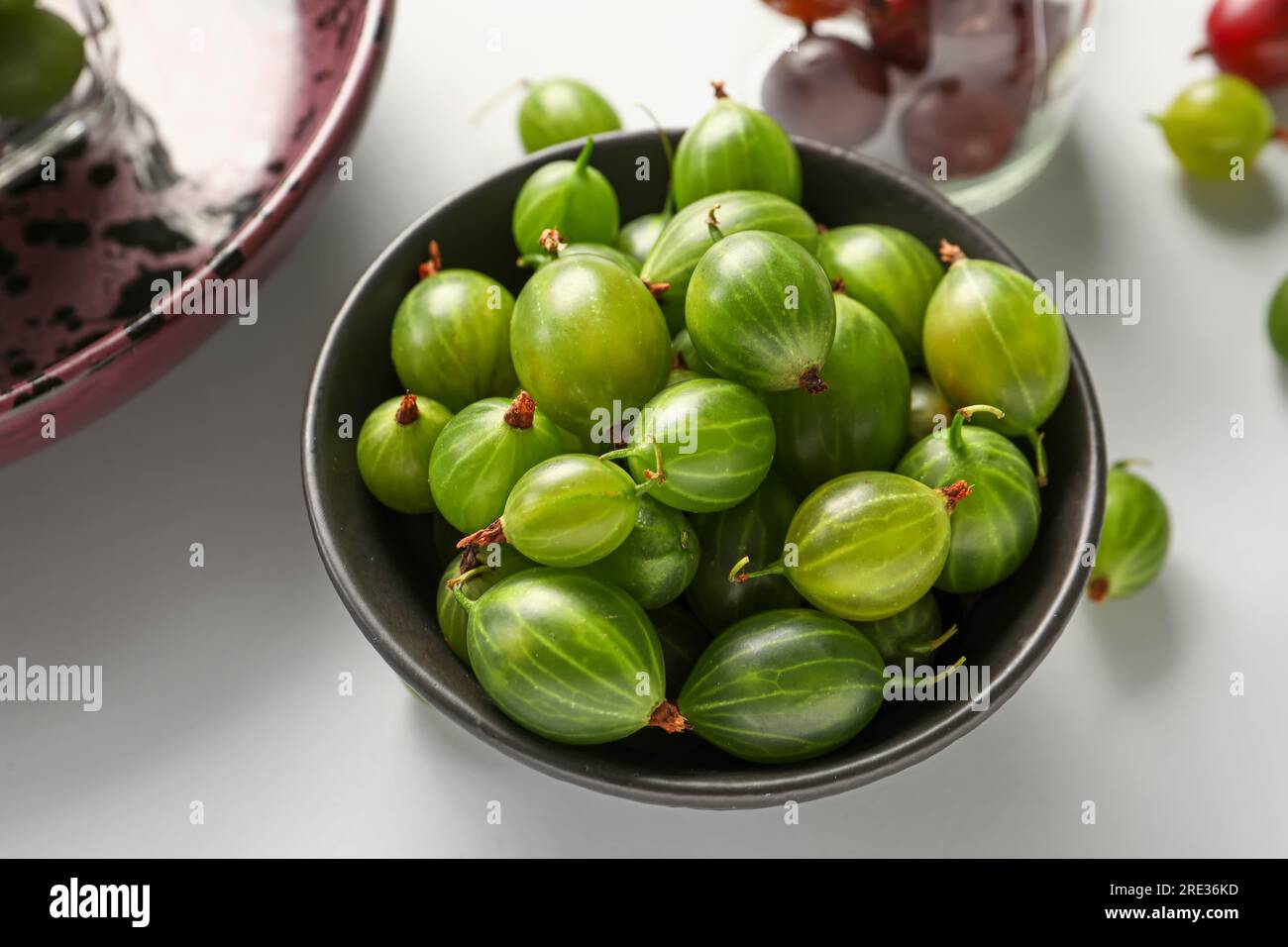 Bowl with fresh gooseberries on white background Stock Photo - Alamy