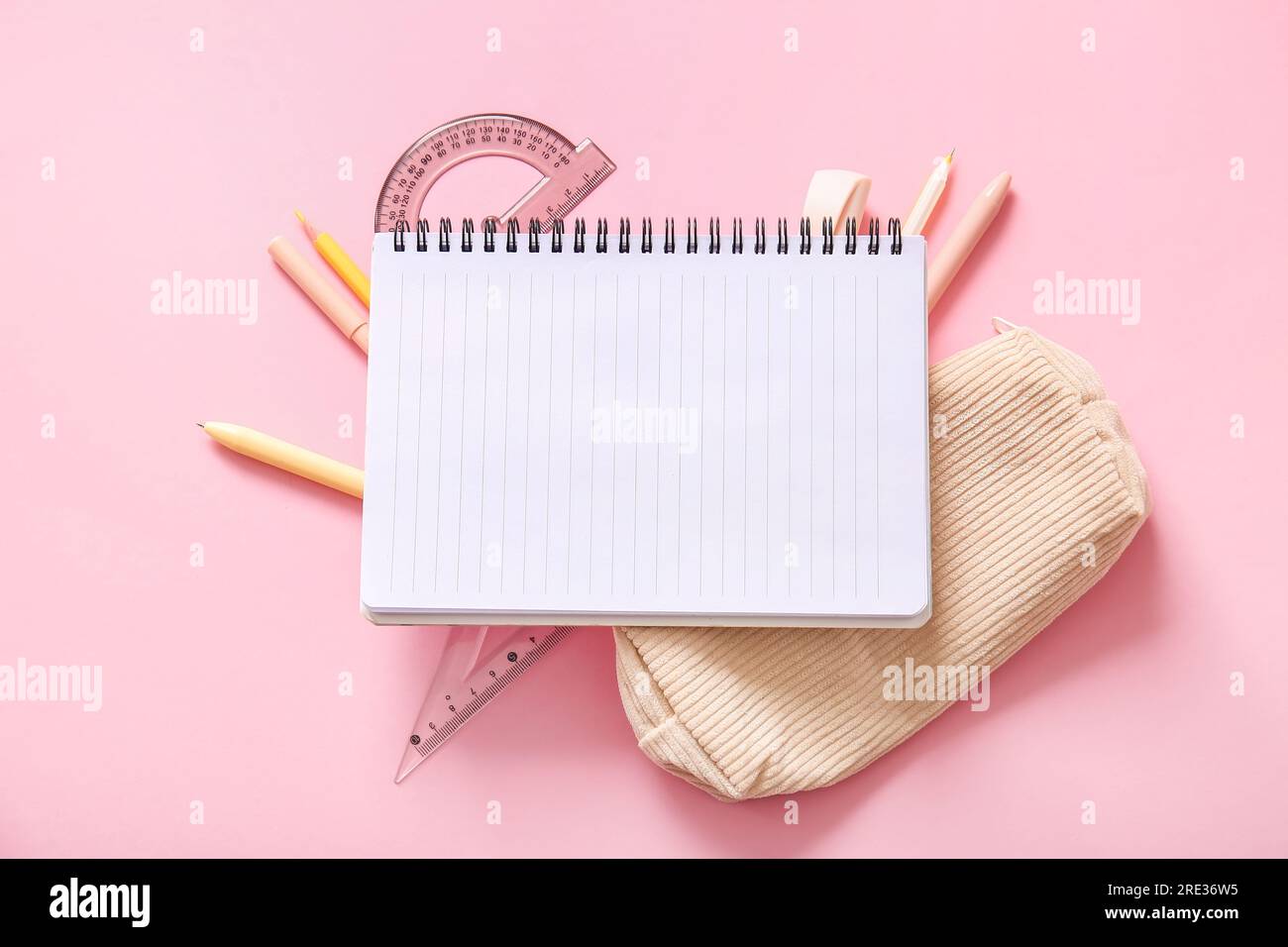 Composition with blank notebook and different school stationery on pink ...