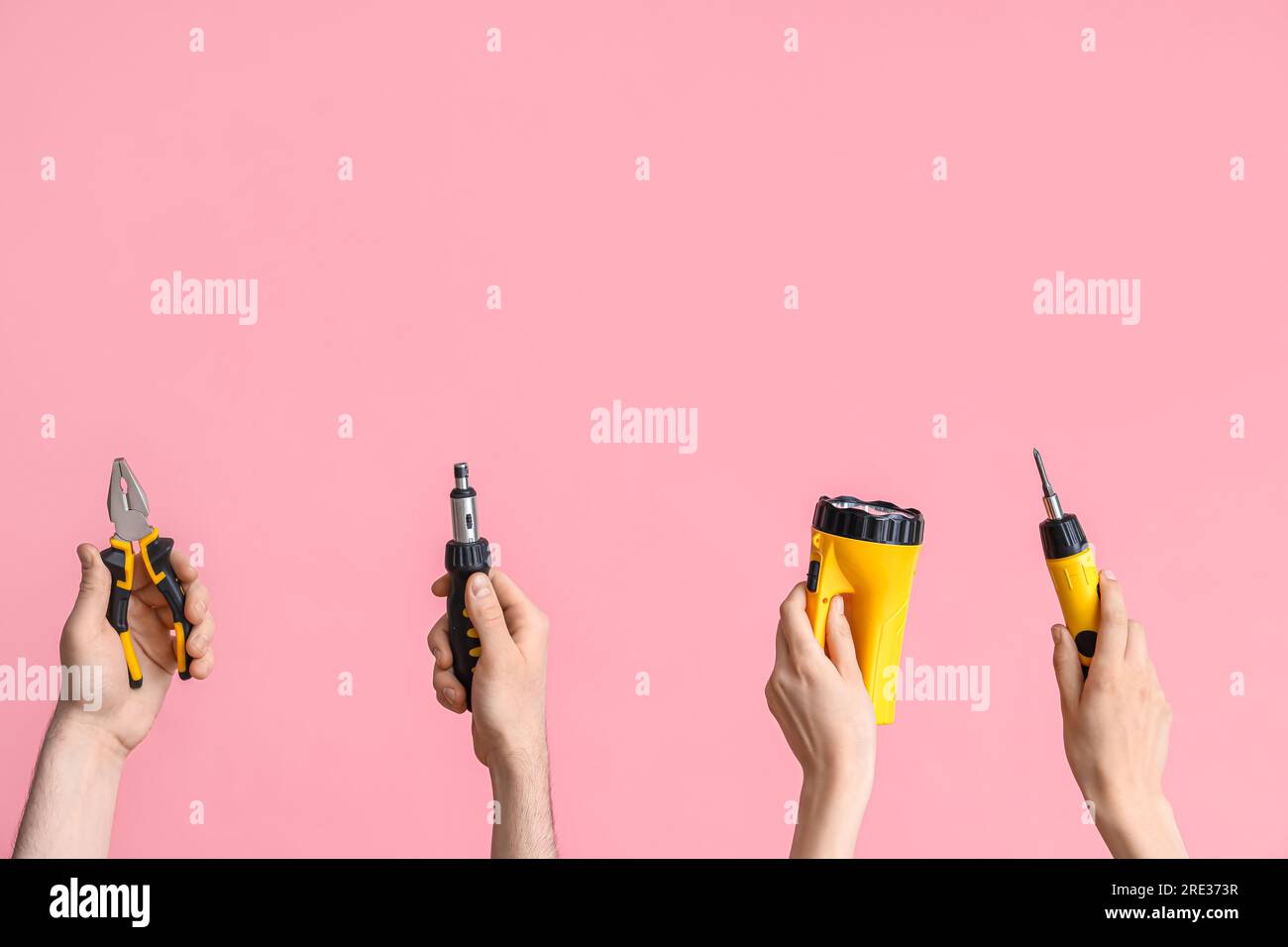 Electrician hands with tools on pink background Stock Photo - Alamy