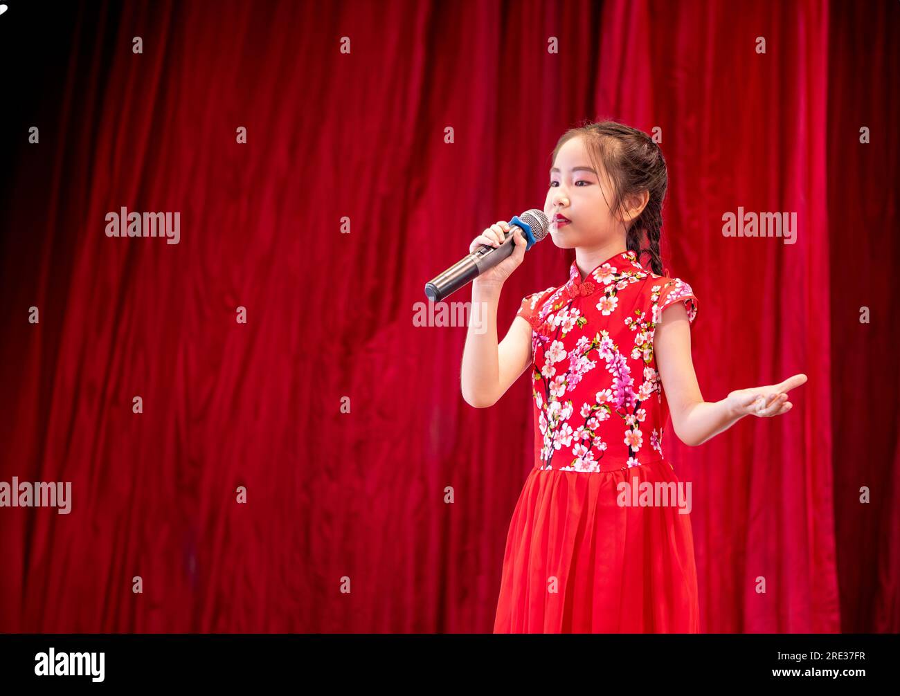 The Asian kid girl sing a song on stage at her school activity day ...