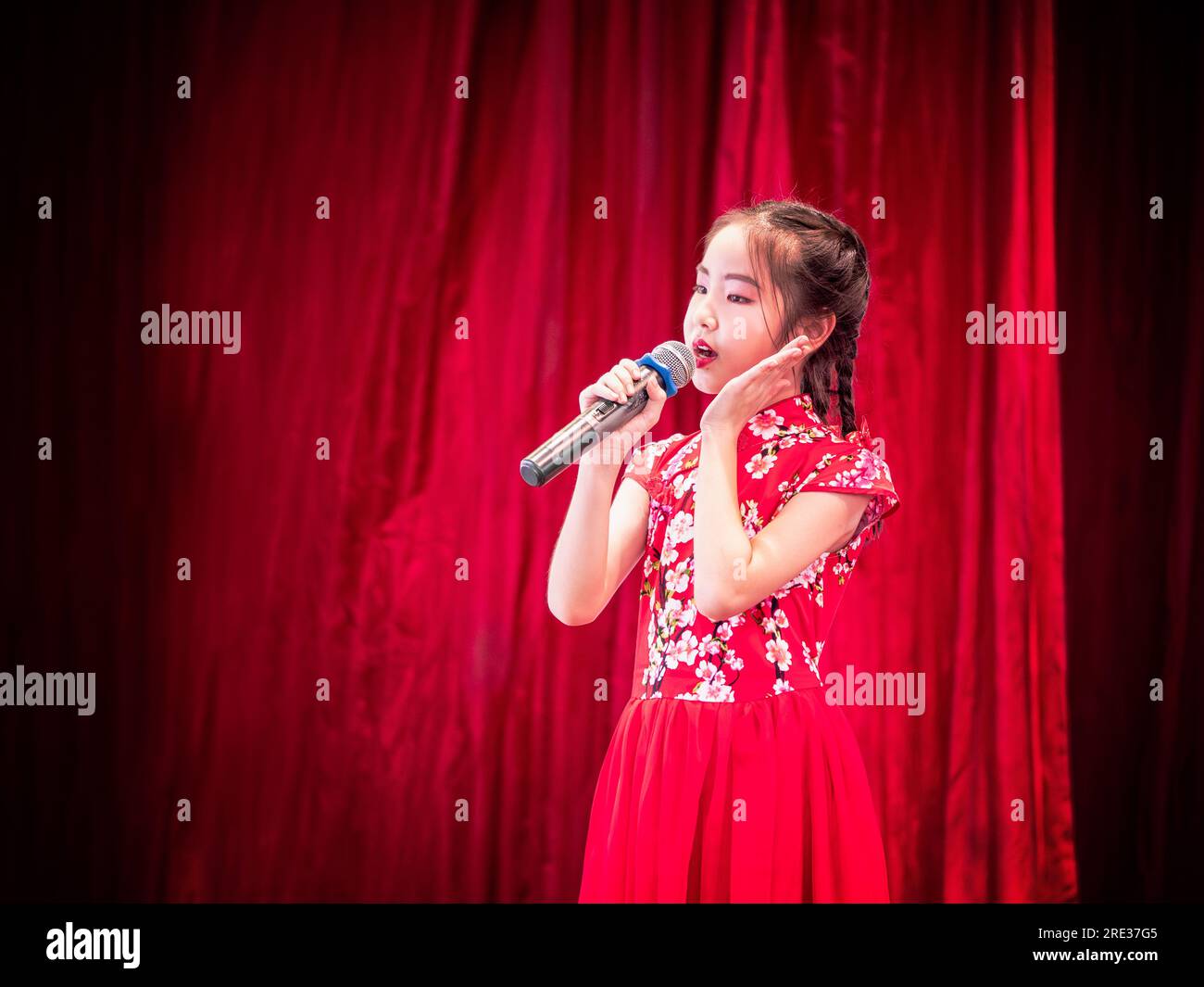 The Asian kid girl sing a song on stage at her school activity day ...