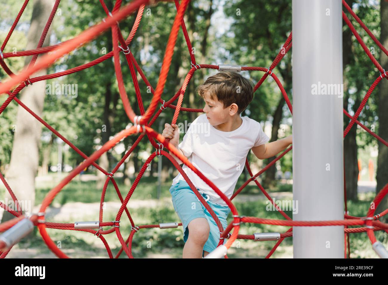 Happy boy child playing in rope spider web at playground Stock Photo ...