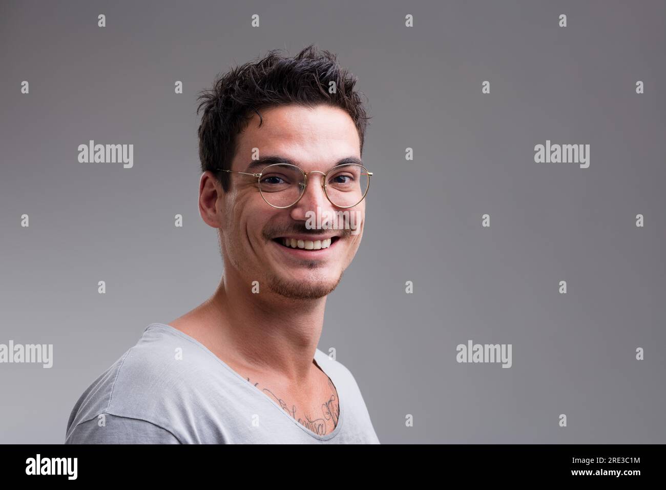 Three-quarter portrait of a young, bespectacled man. His muscular build ...