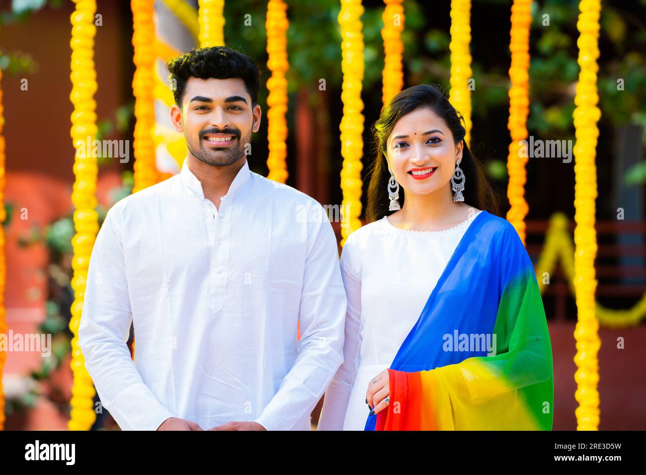 Happy smiling indian couple standing with looking at camera at flower ...