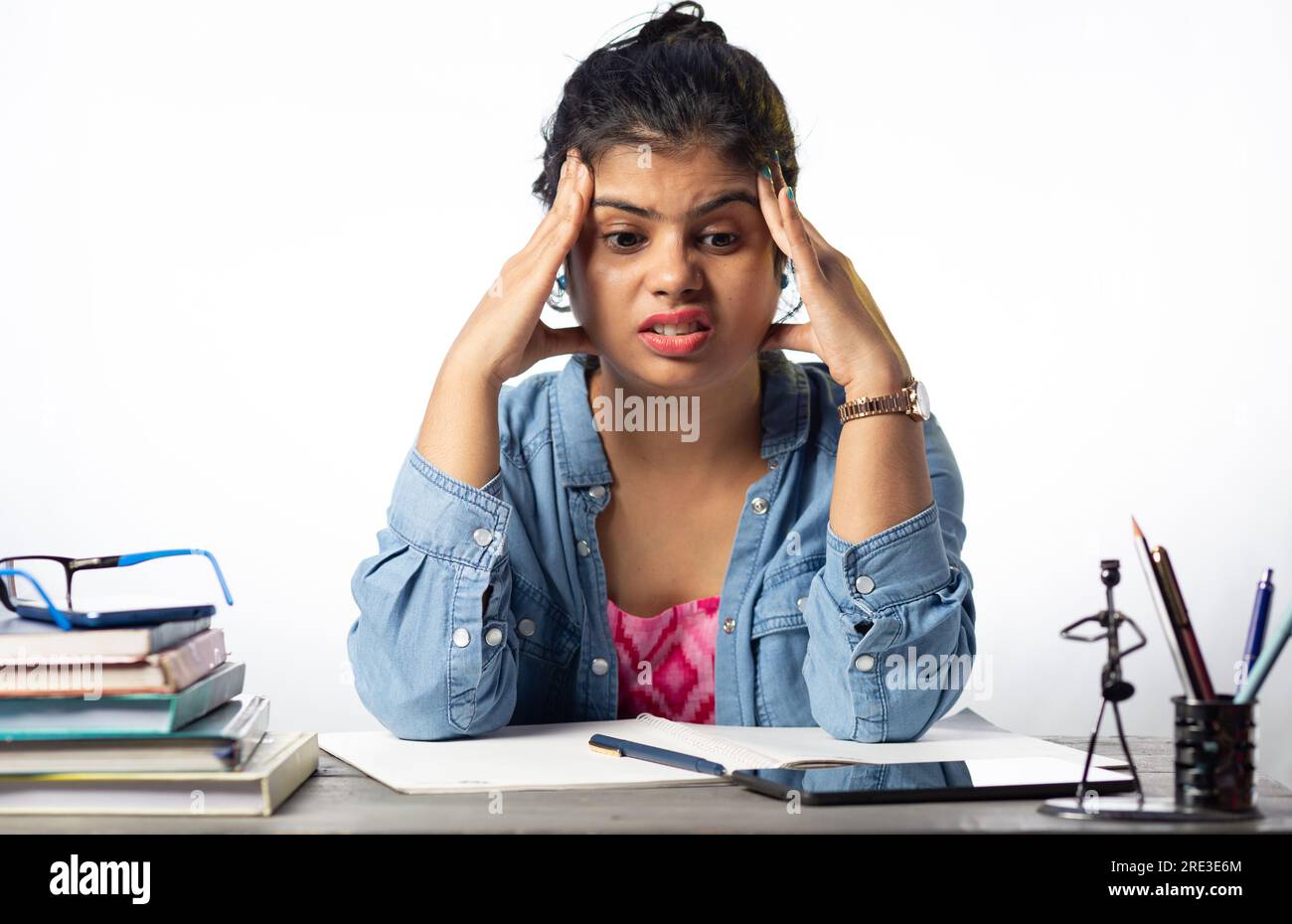 A pretty young Indian college student holding head for study load while ...