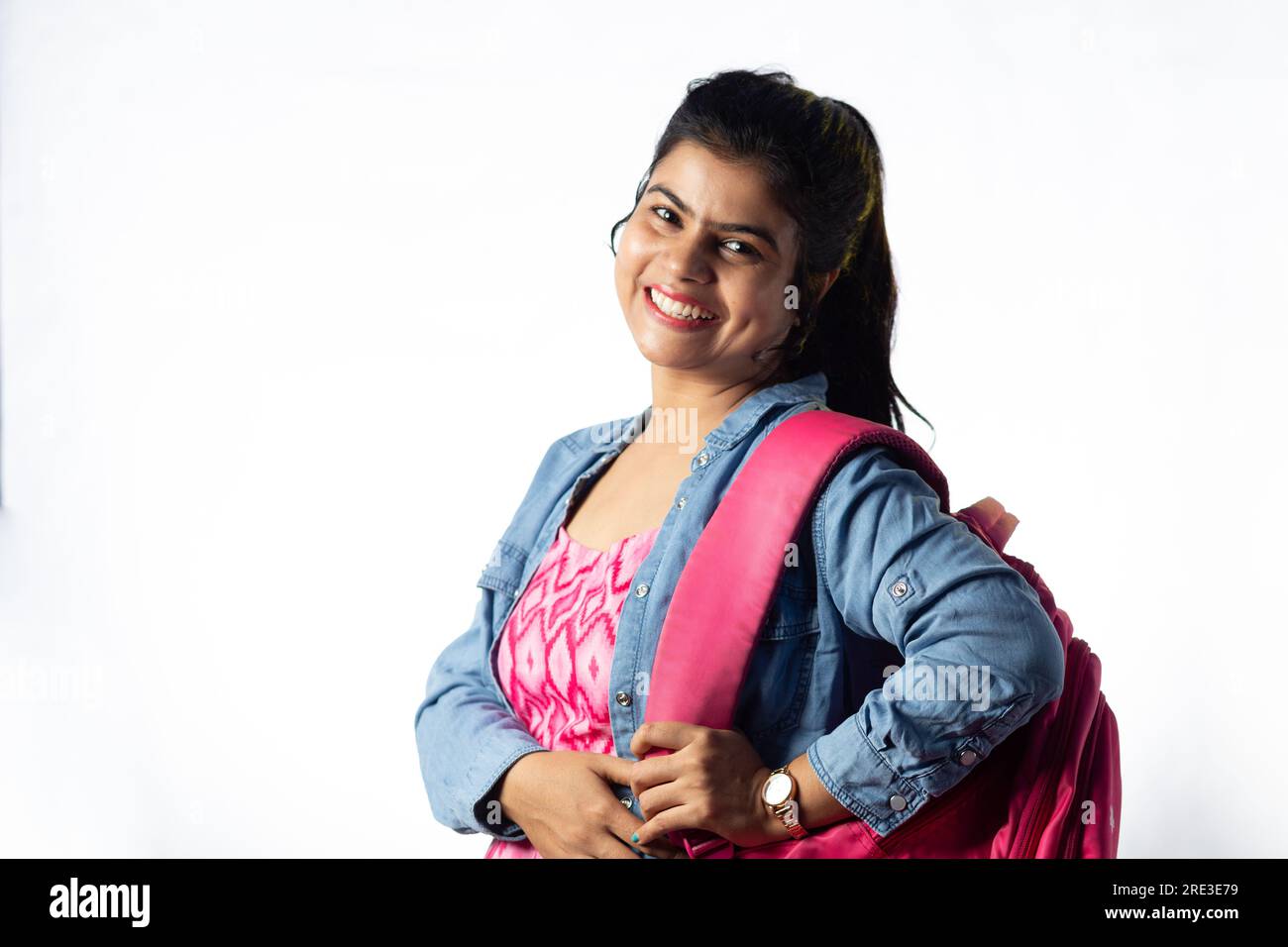 A pretty young Indian girl with backpack standing with smiling face on ...