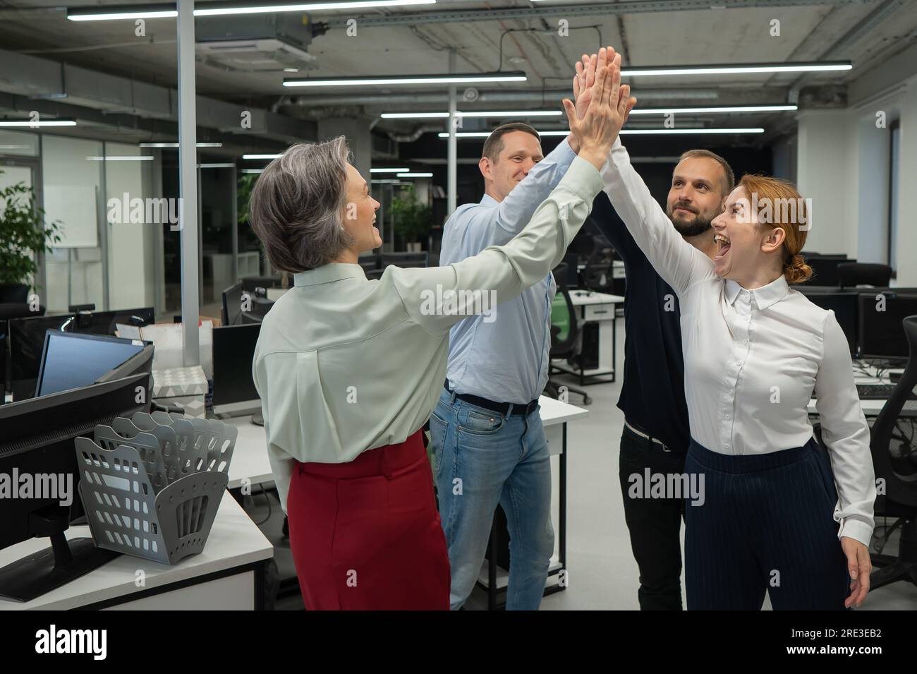 Four co-workers give a high five in the office Stock Photo - Alamy