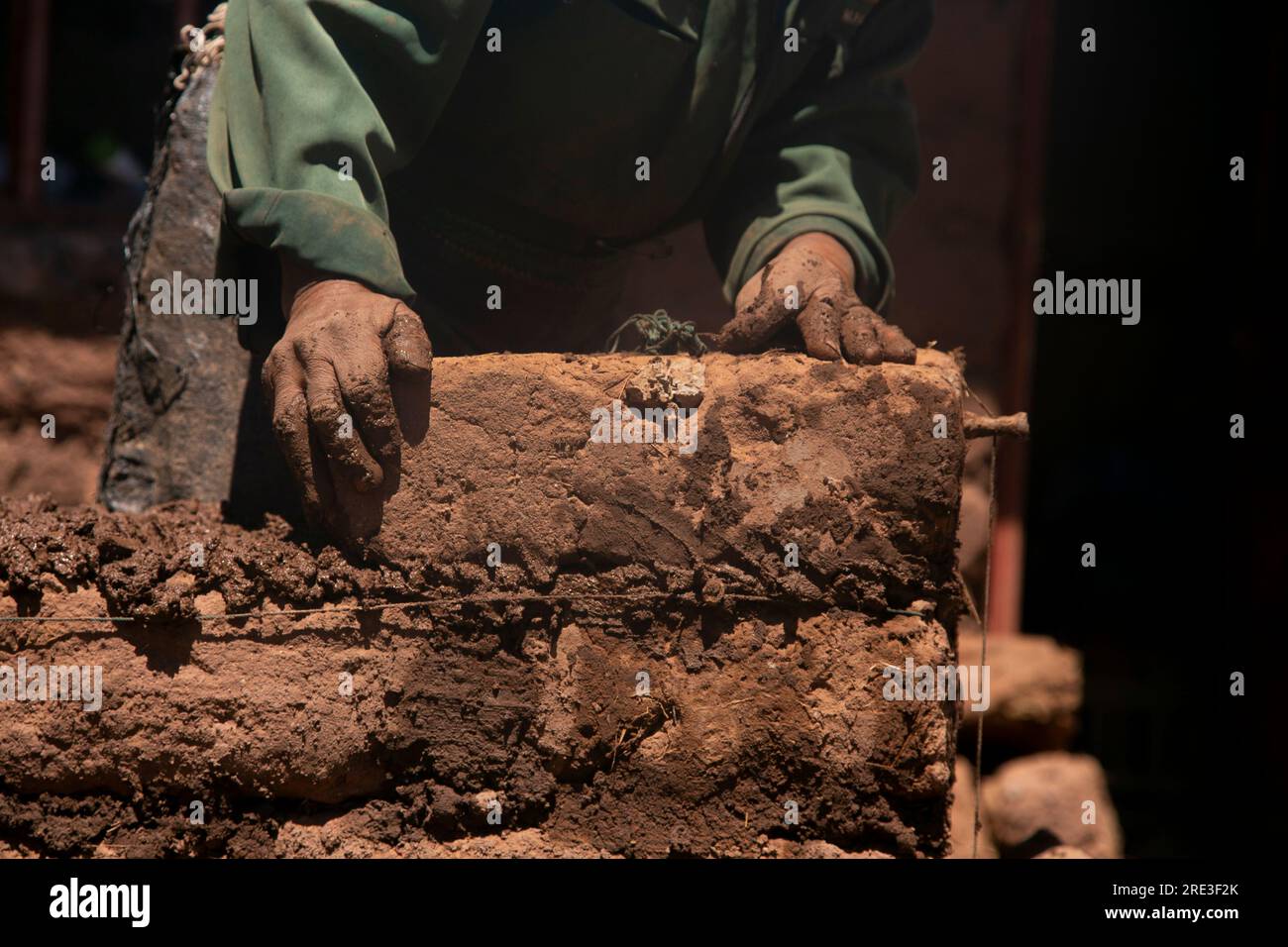 Man building with his hands an adobe house with adobe bricks and mud ...