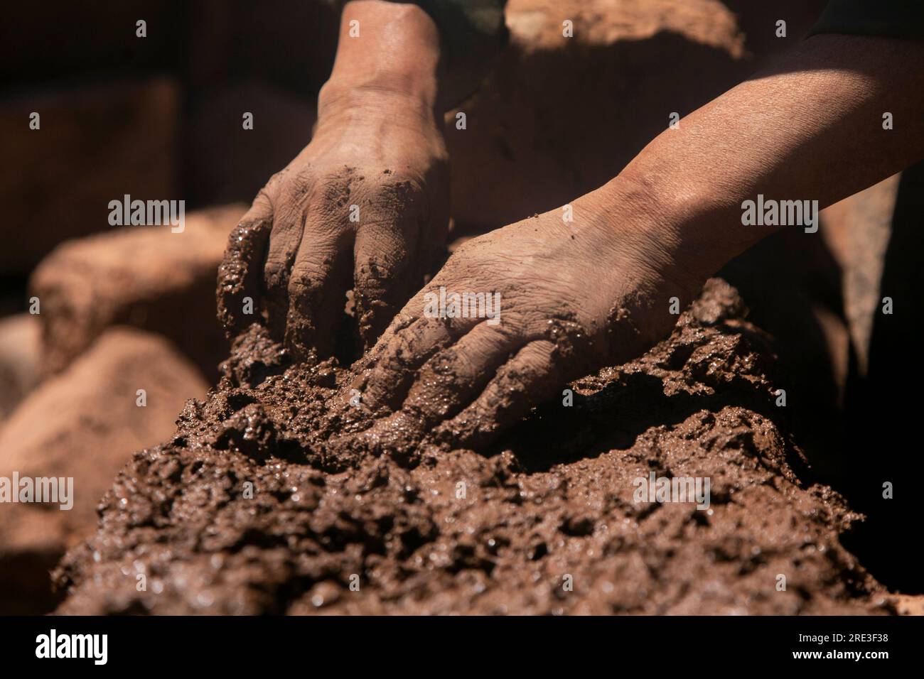 Man building with his hands an adobe house with adobe bricks and mud ...