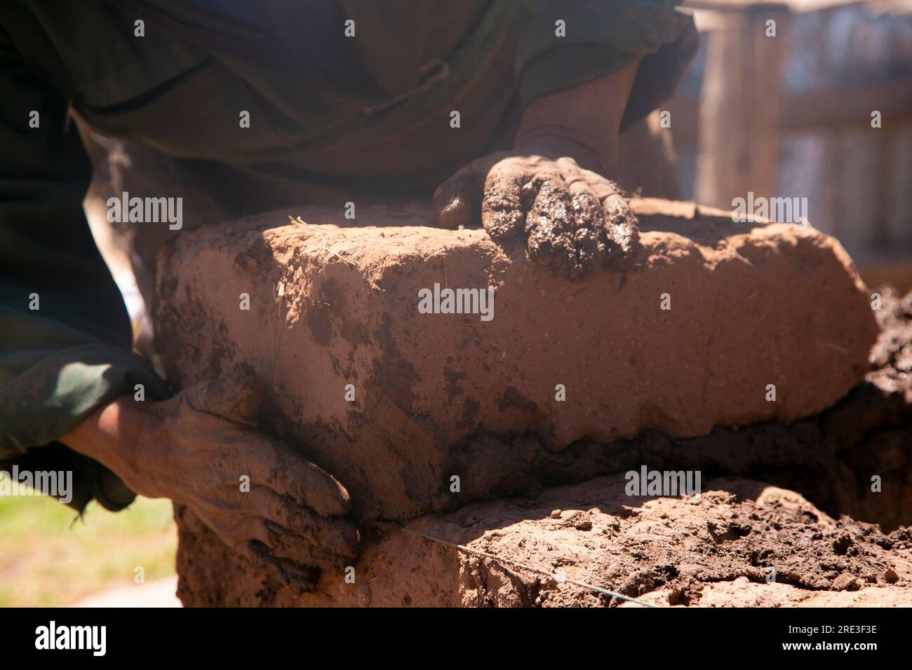 Man building with his hands an adobe house with adobe bricks and mud ...