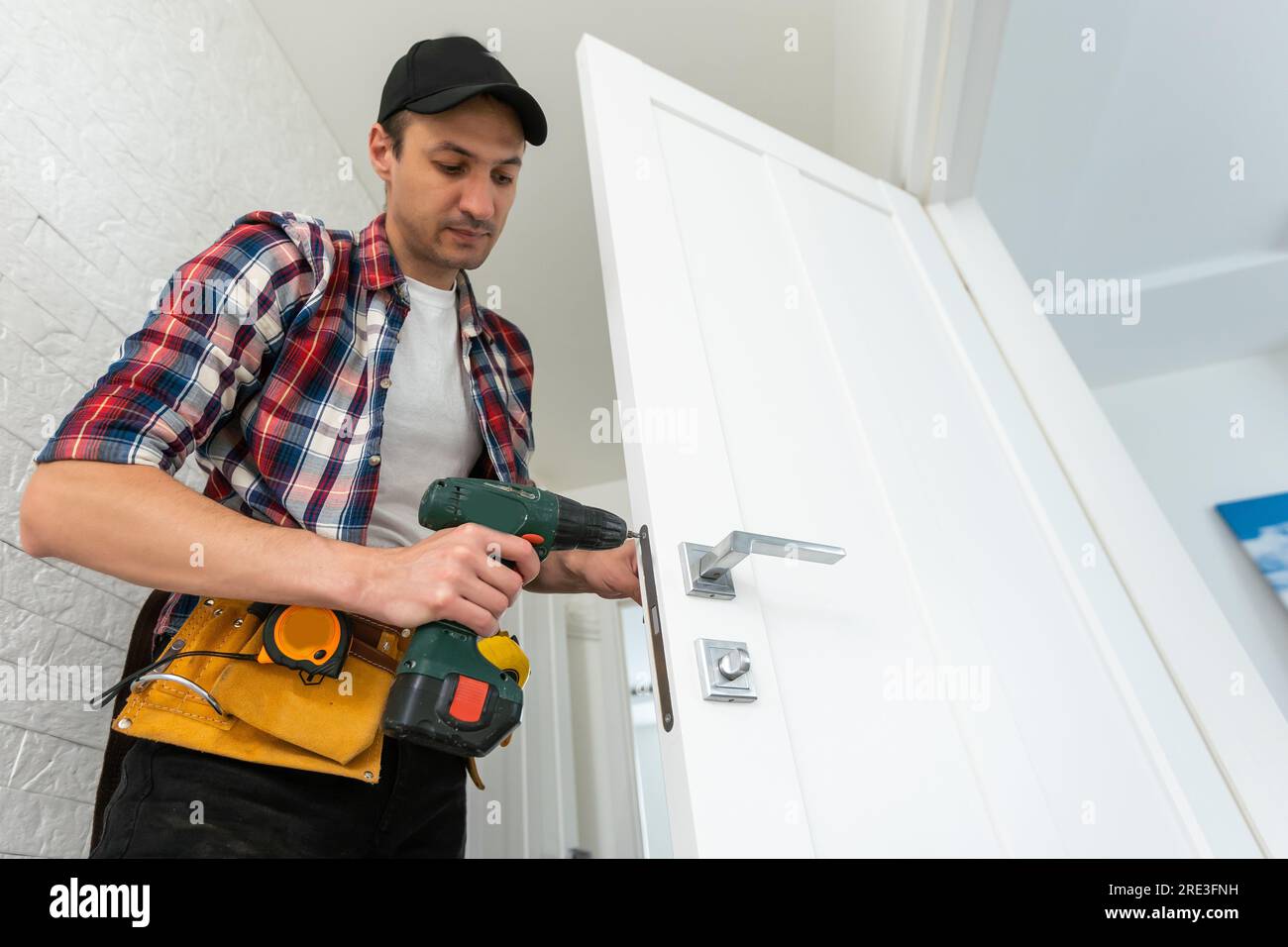 Carpenter repairing door lock. Installing a door handle Stock Photo - Alamy