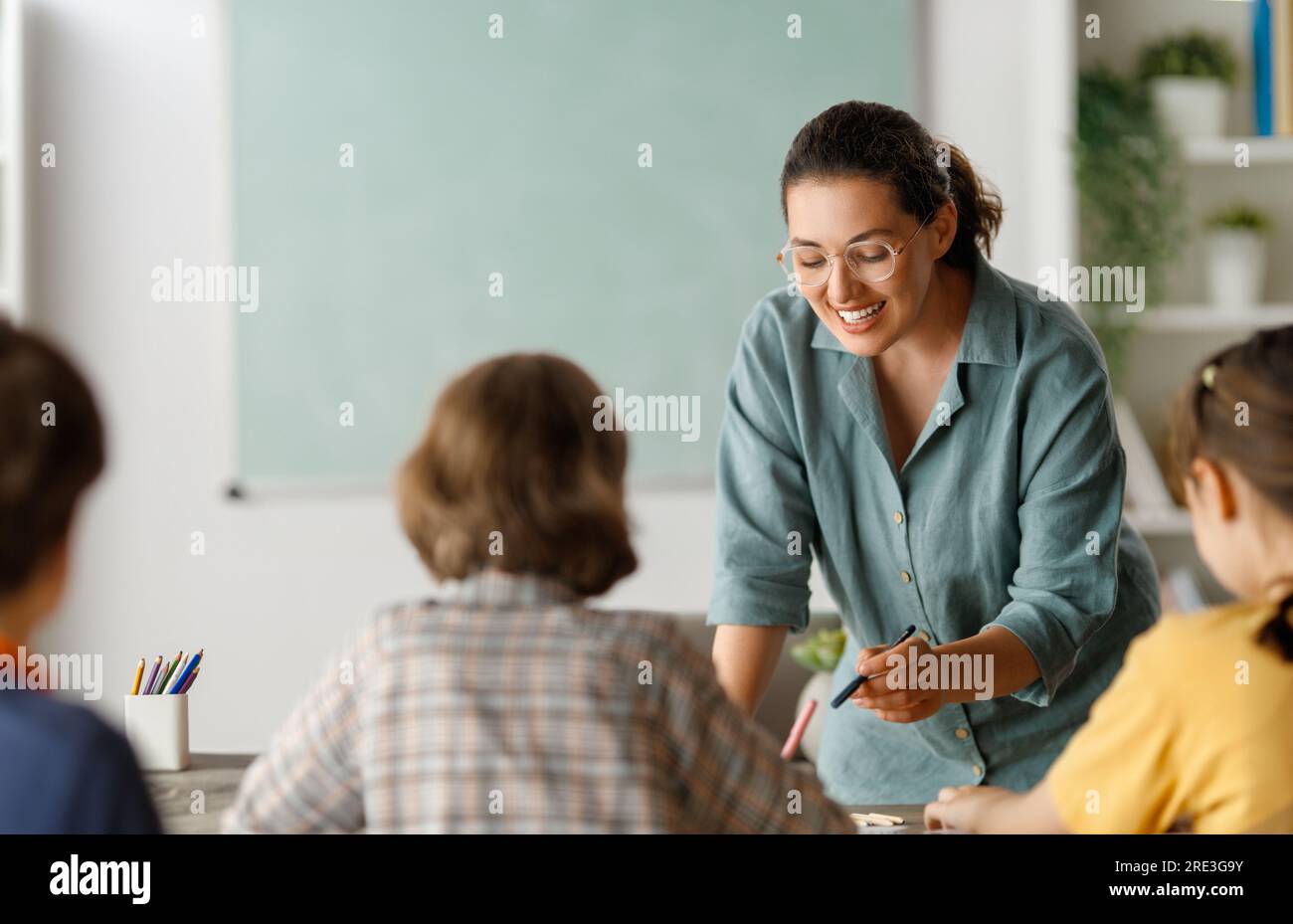 Happy kids and teacher at school. Woman and children are talking in the ...