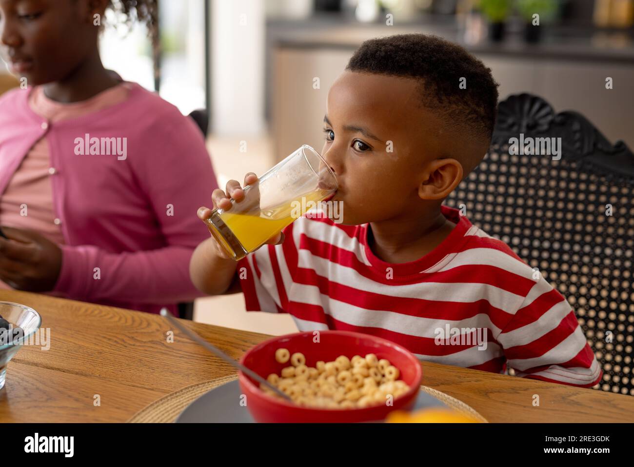 African american brother and sister eating breakfast in dining room at ...