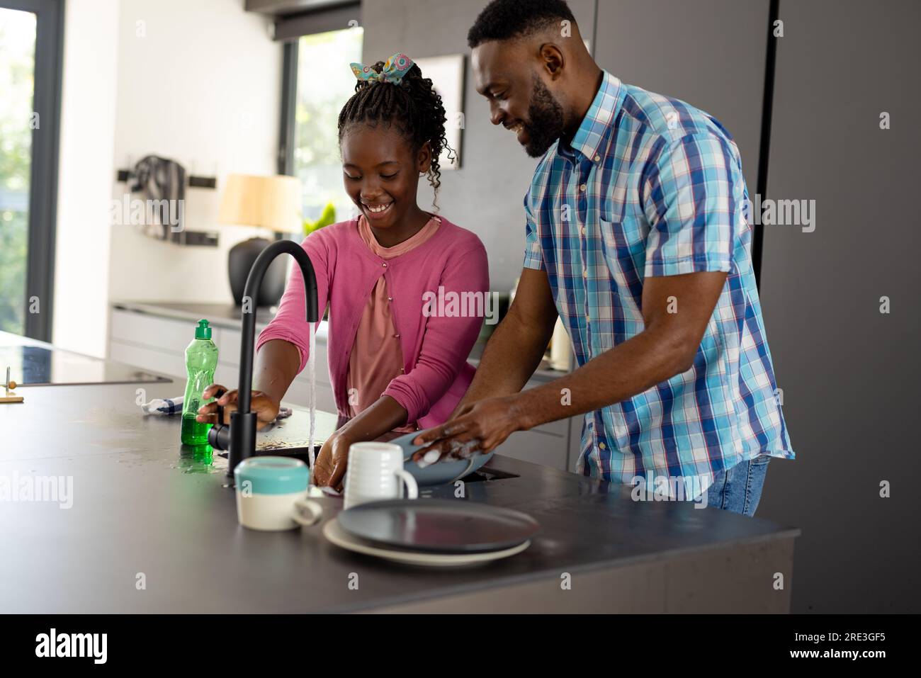 Happy african american father and daughter washing dishes in kitchen at ...