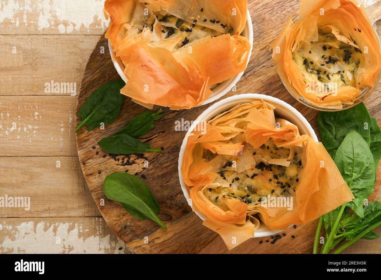 Filo pies with soft feta cheese and spinach in ceramic molds on old ...
