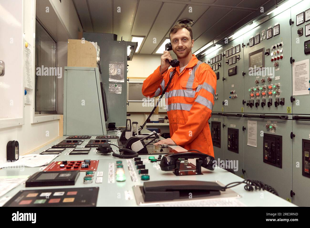 Young marine specialist performing radio checks in engine control room ...