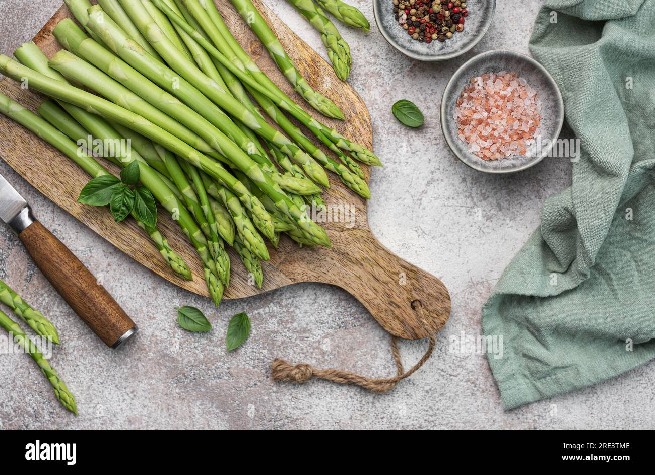 Bunch of raw asparagus stems with different spices on grey concrete ...