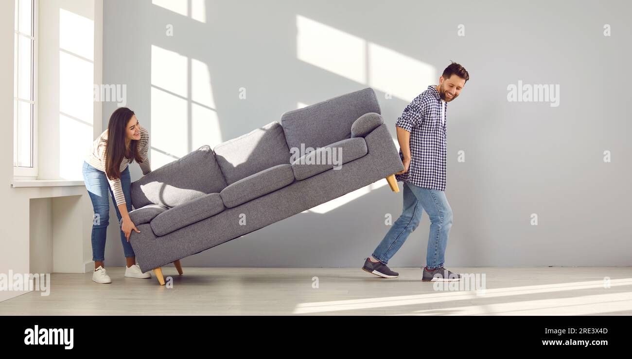 Happy couple placing sofa in living room of new home Stock Photo - Alamy
