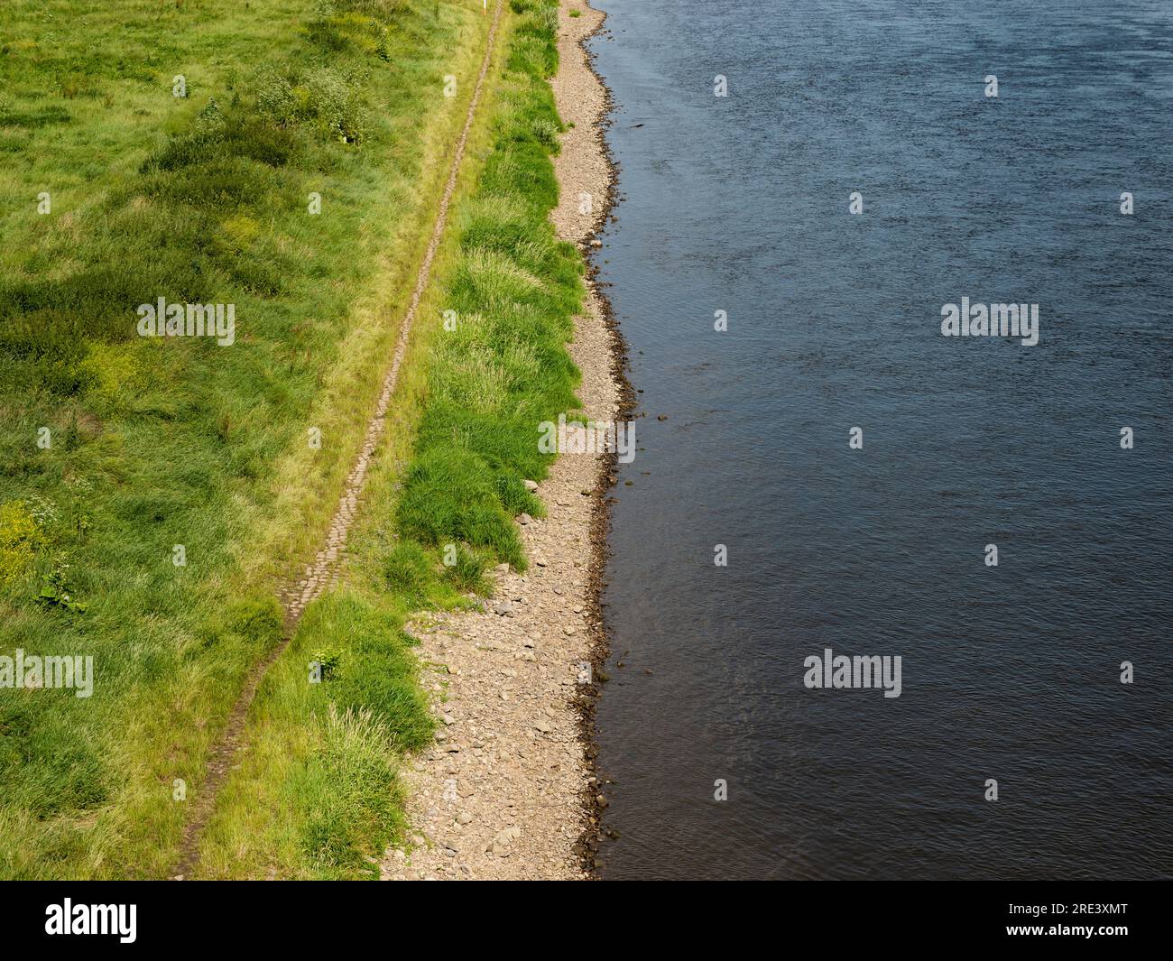 Shore line of a river or lake with grass, stones and water. Beautiful ...