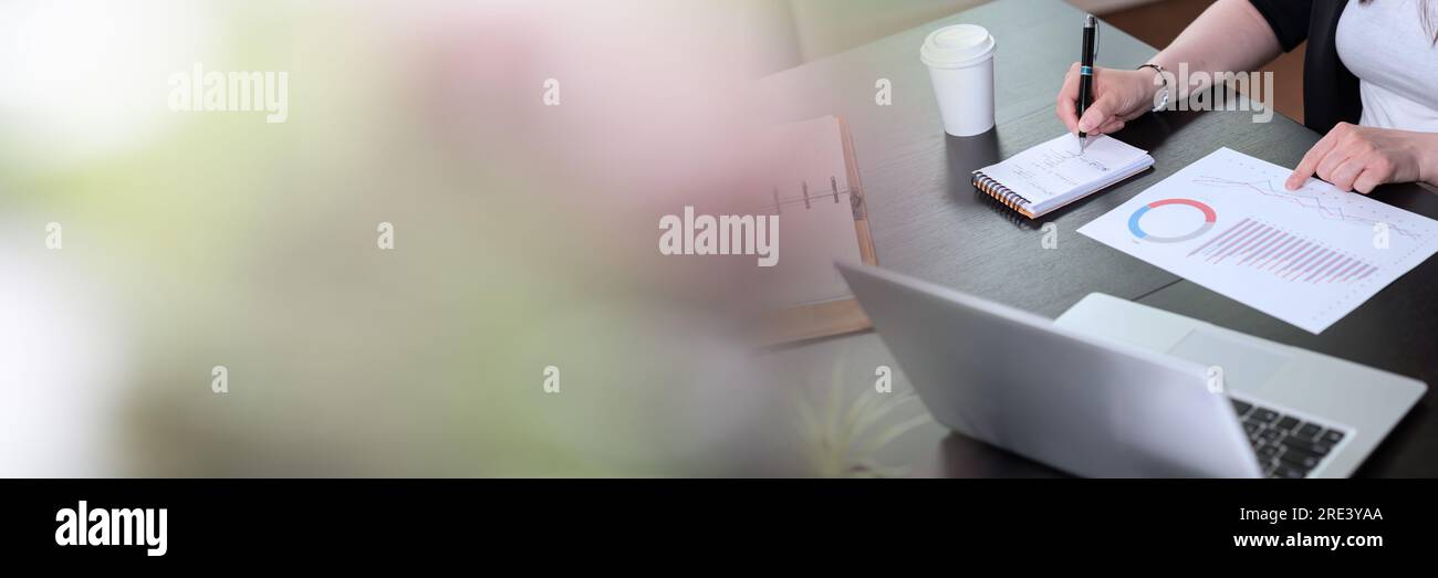Businesswoman analysing marketing data and taking notes; panoramic ...