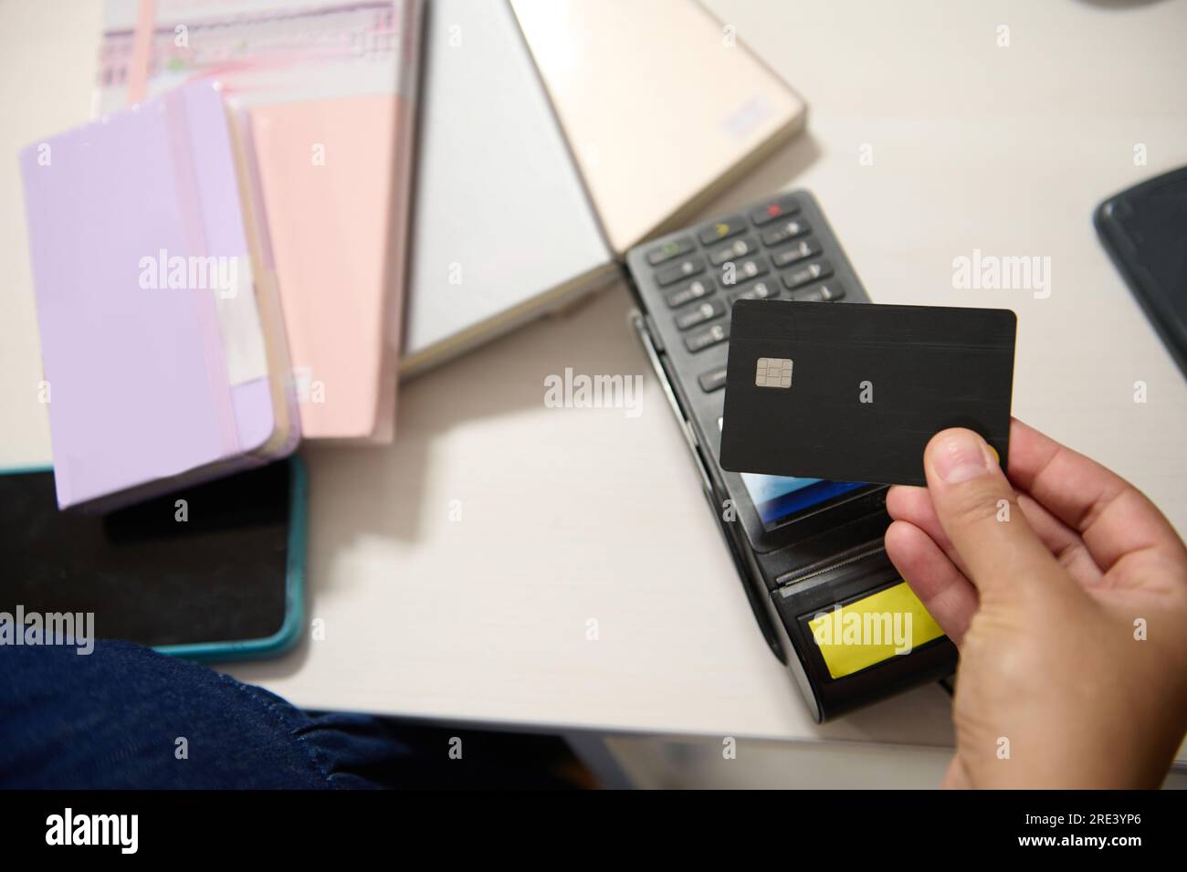 Close-up hand holding black blank mockup credit card over a POS ...