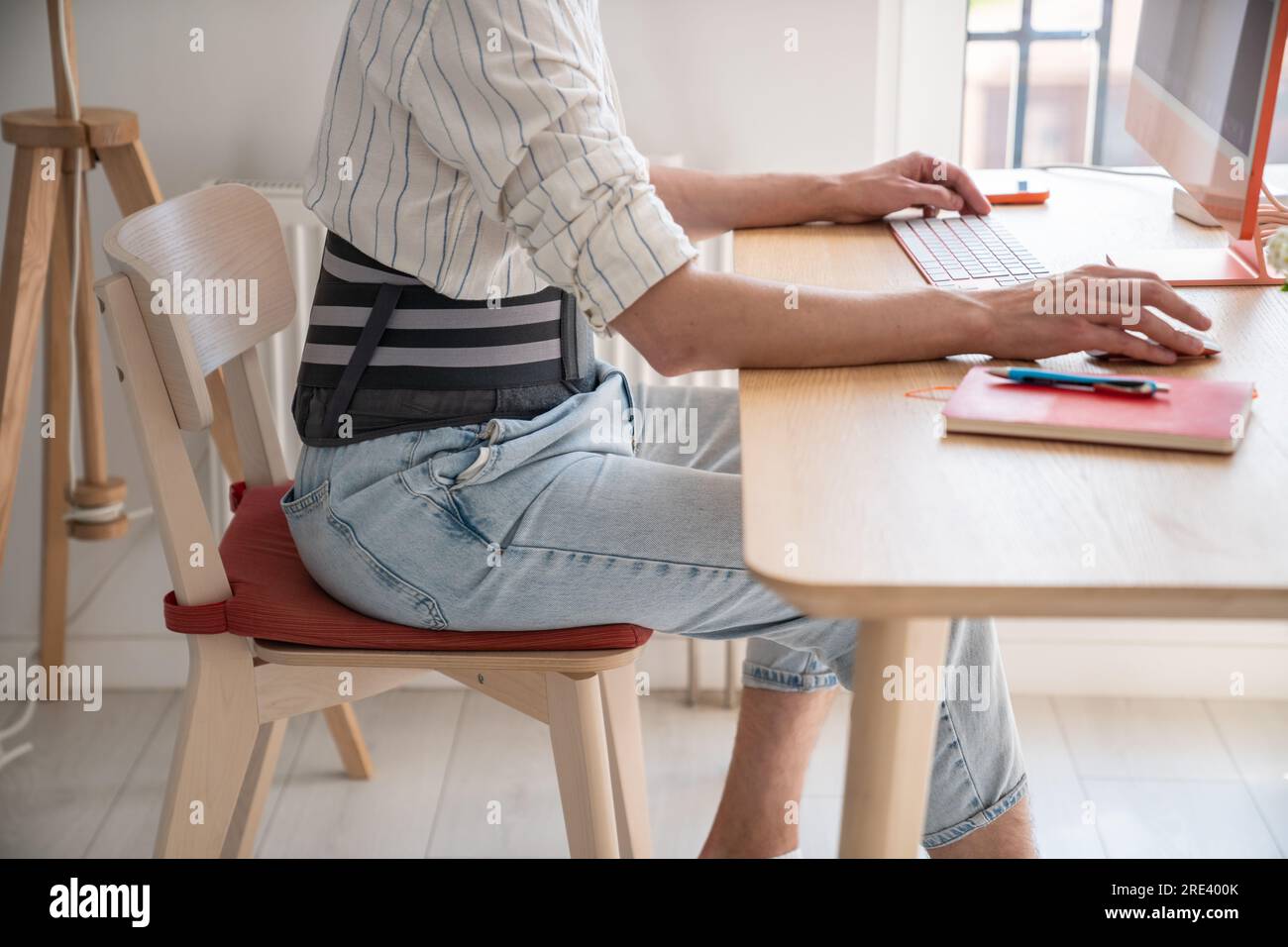 Man works on computer wears back support belt on lower back to relieve ...