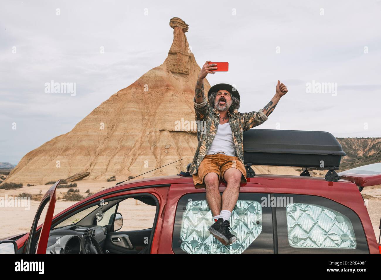Tourist sitting on top of a van using a mobile camera to take one with ...