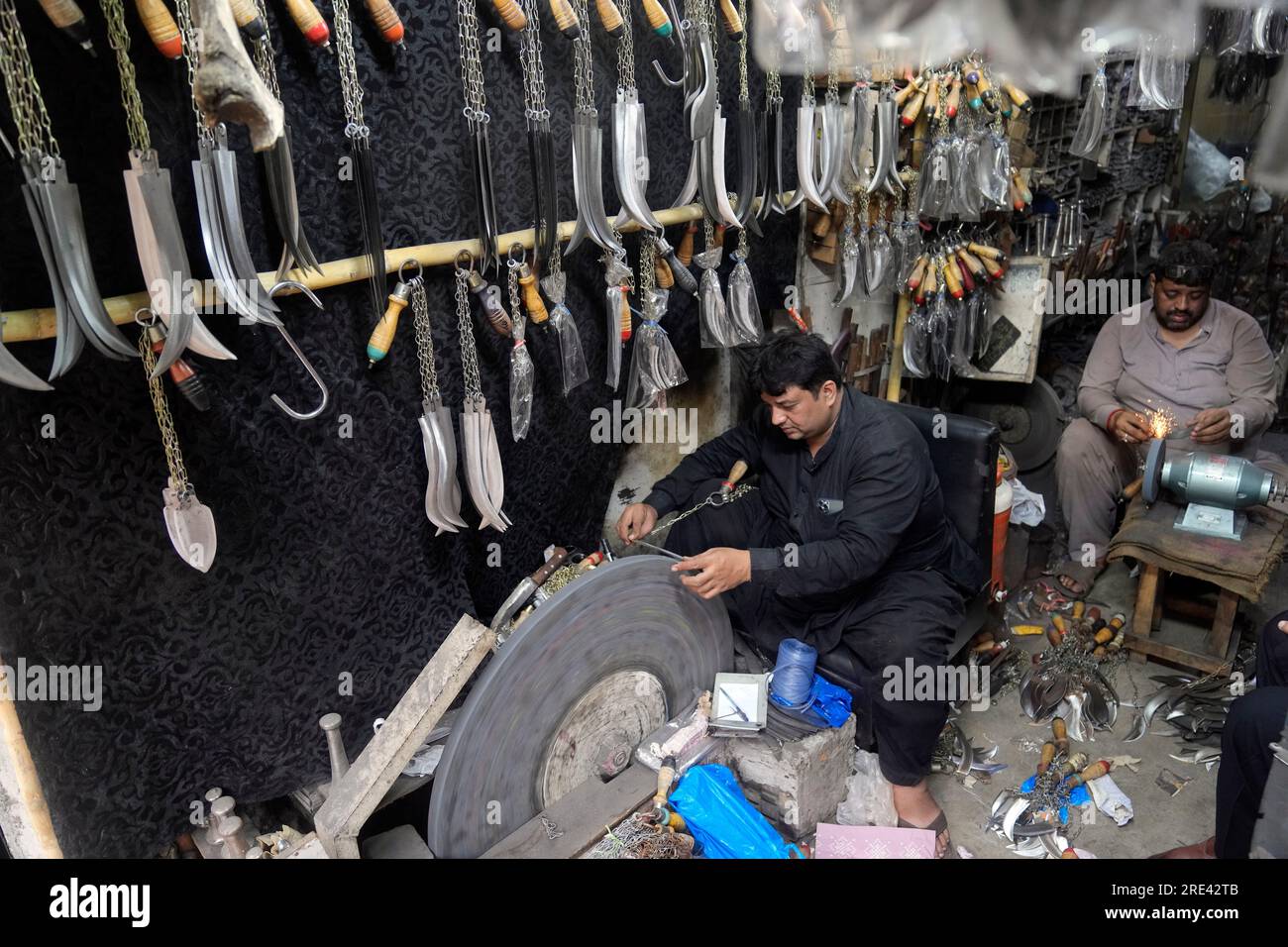 Pakistani iron smiths sharpen knives, as bunches of knives and chains ...